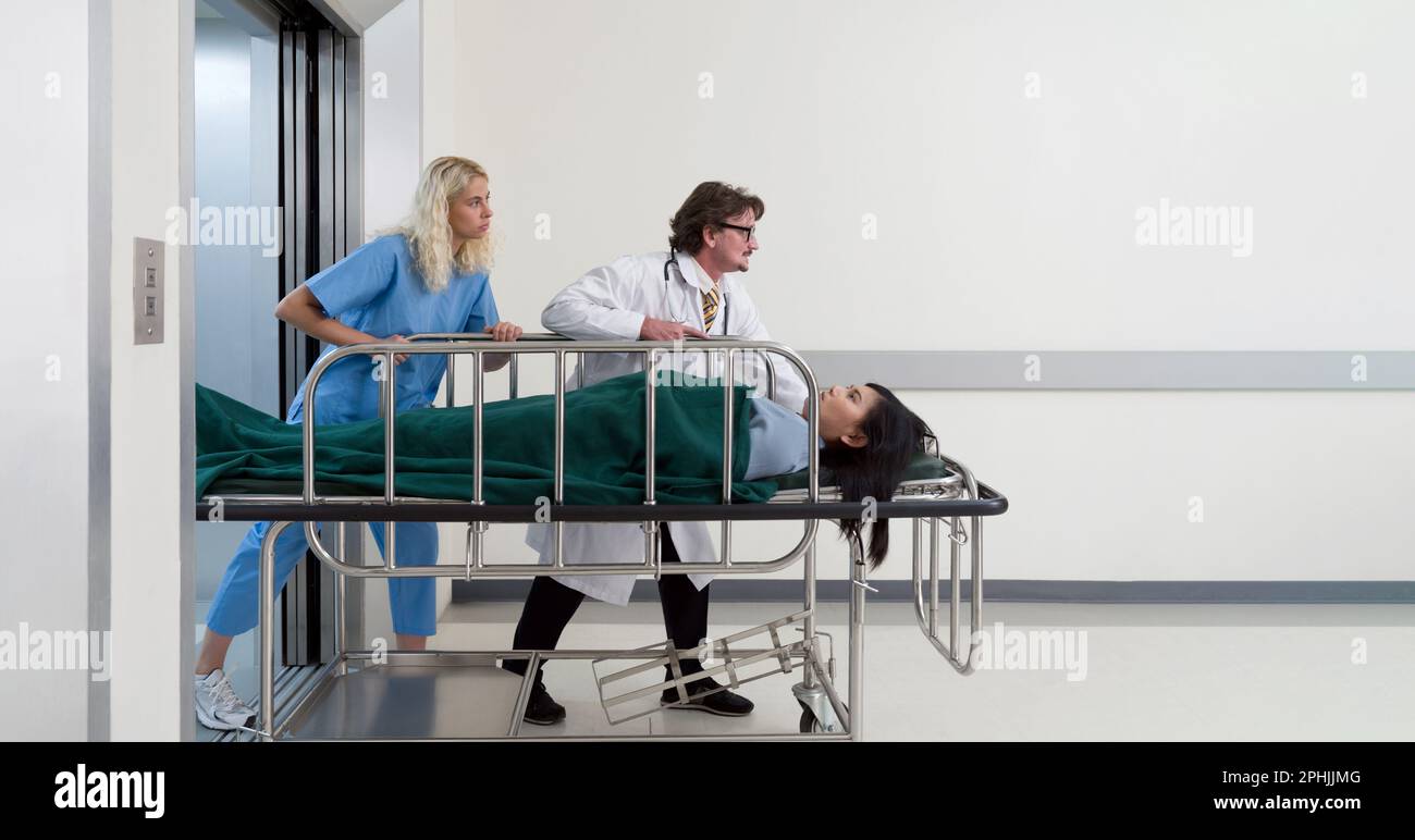 Nurse and paramedic pushing the patient bed out of the elevator to the ...
