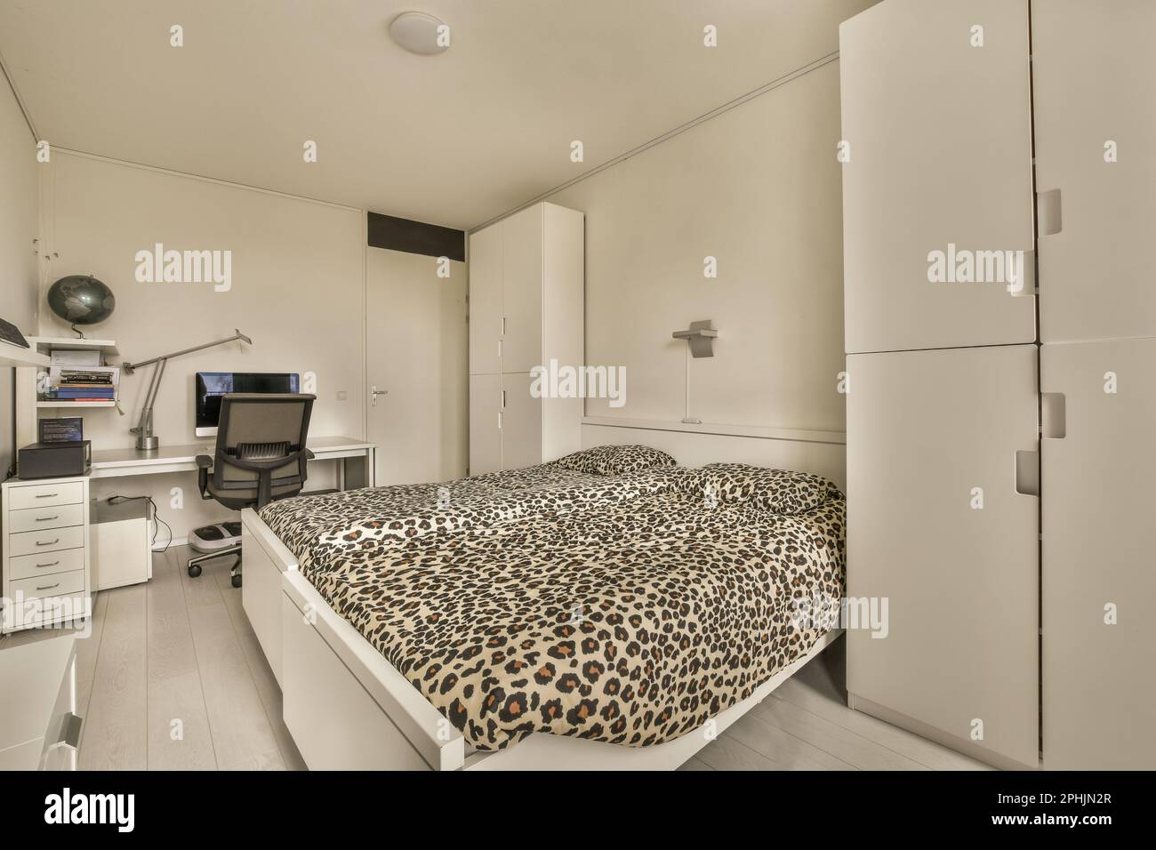 a bedroom with a bed, desk and computer monitor on the wall in it's ...