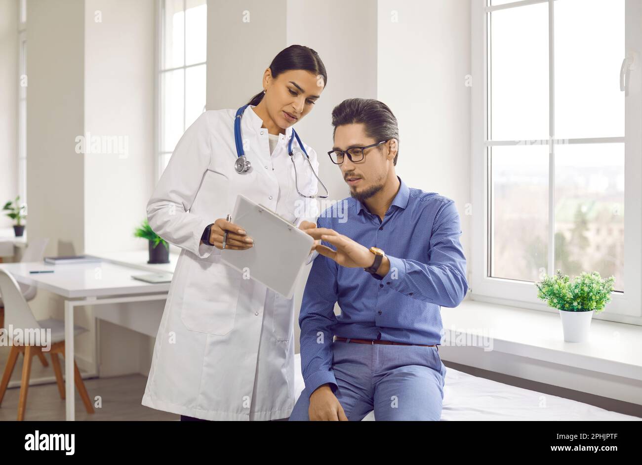 Doctor showing medical checkup results to man sitting on bed in ...
