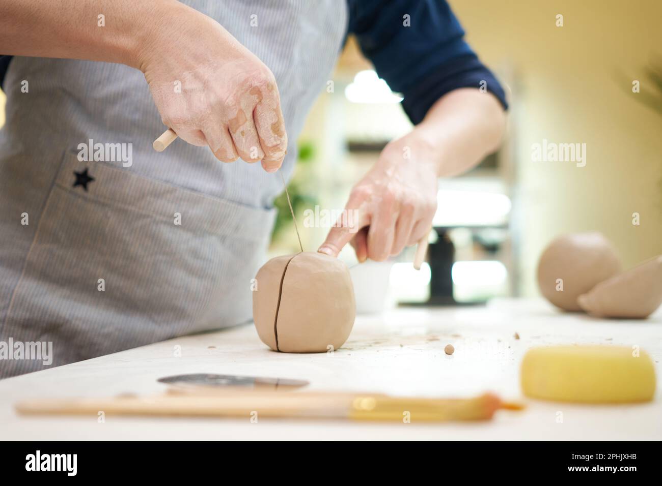female potter cutting clay with thread at pottery studio Stock Photo ...