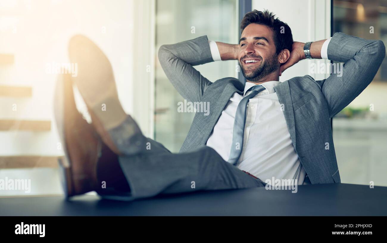 Another great day for business. a businessman leaning back in his chair ...