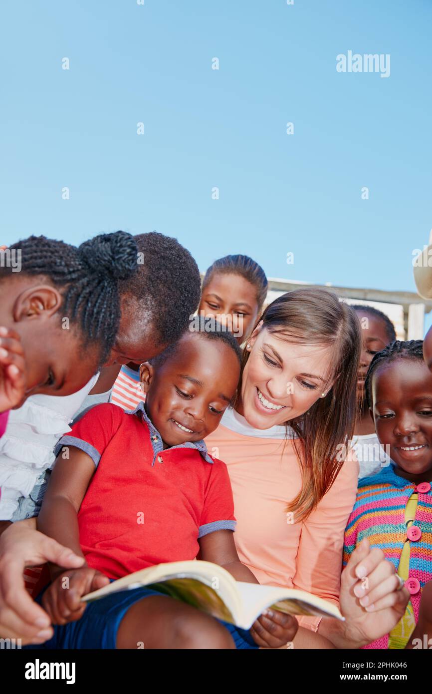 Hes learning how to read. a volunteer worker reading to a group of ...