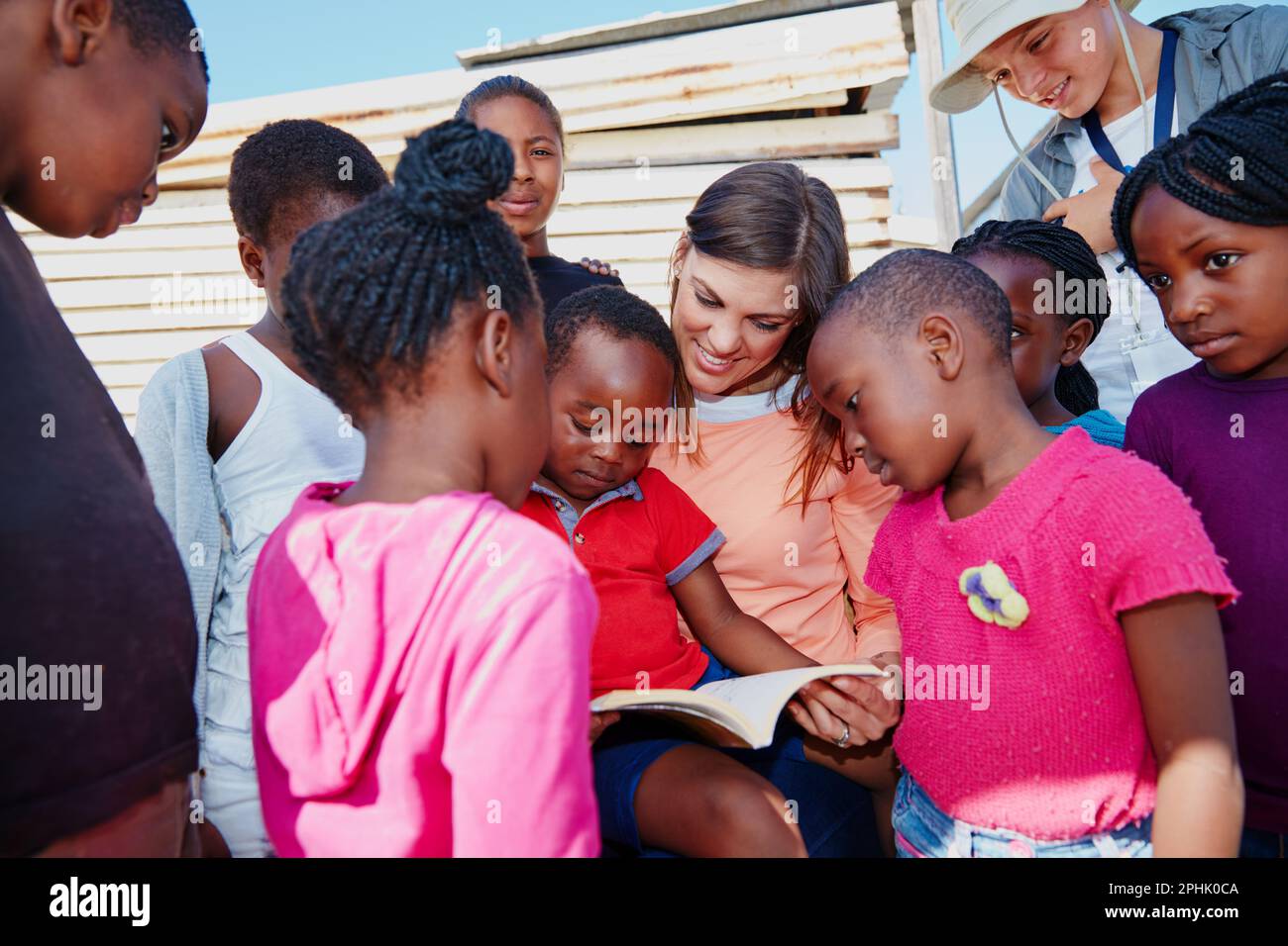 Teaching them how to read. a volunteer worker reading to a group of ...