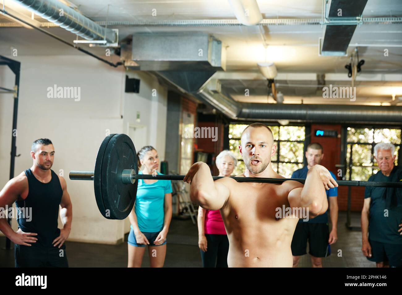 Stronger every day. a man lifting weights while a group of people in ...