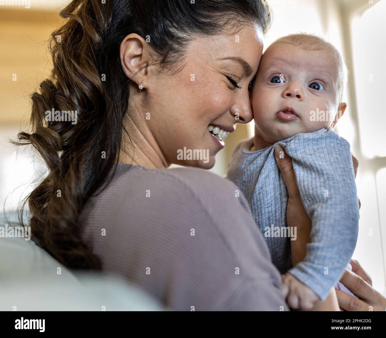 Smiling pretty mum holding infant and enjoying tender quiet moment in ...
