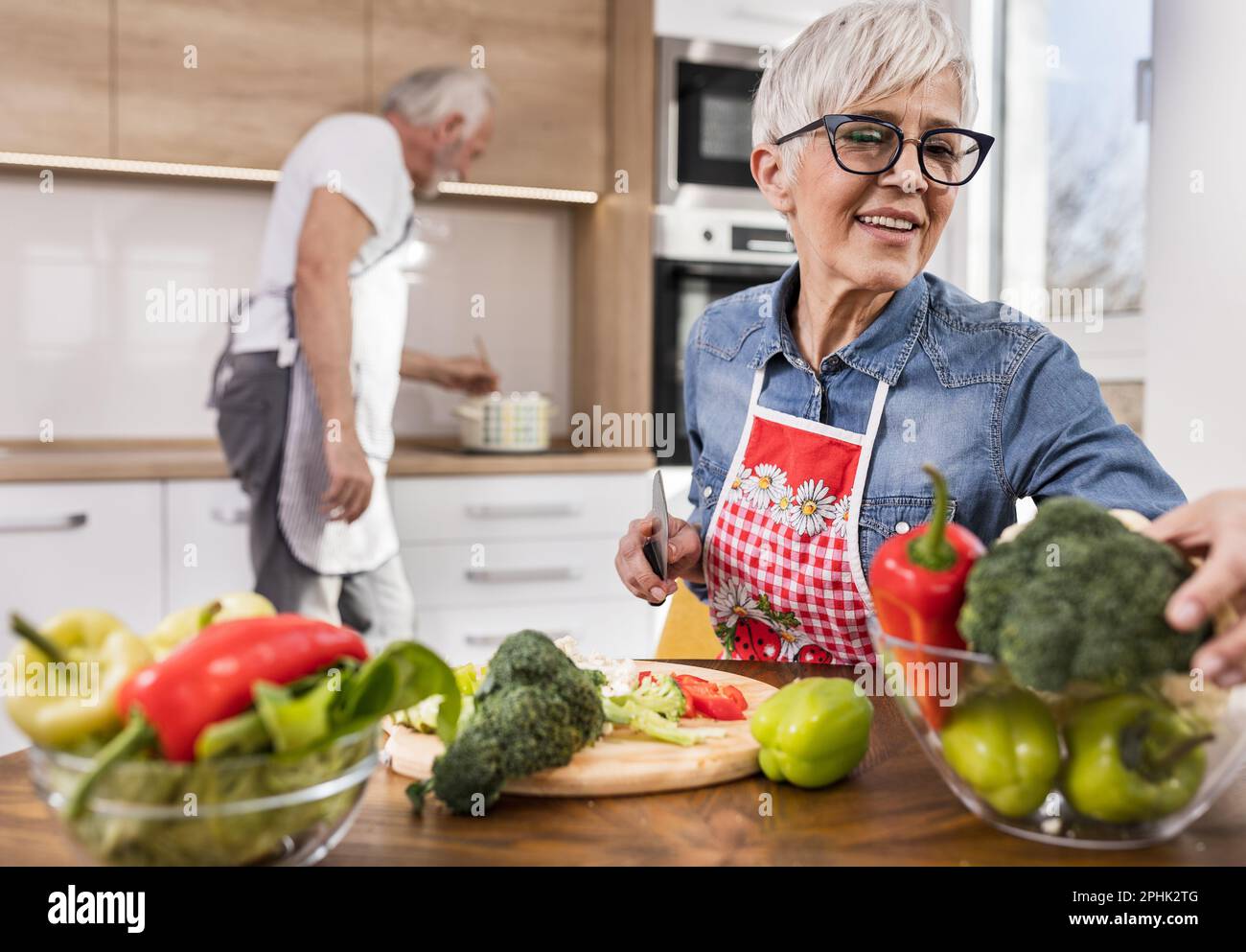 Senior couple preparing soup, wife cutting vegetable while husband ...