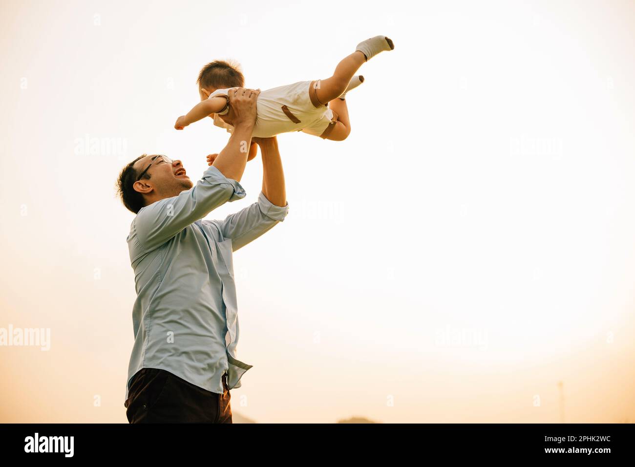Father holds his baby daughter up high throwing up Stock Photo - Alamy