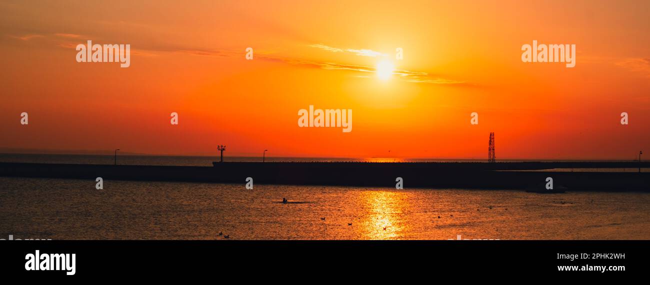 Reflection of sunlight over sea surface at sunset. Orange and gold blue ...