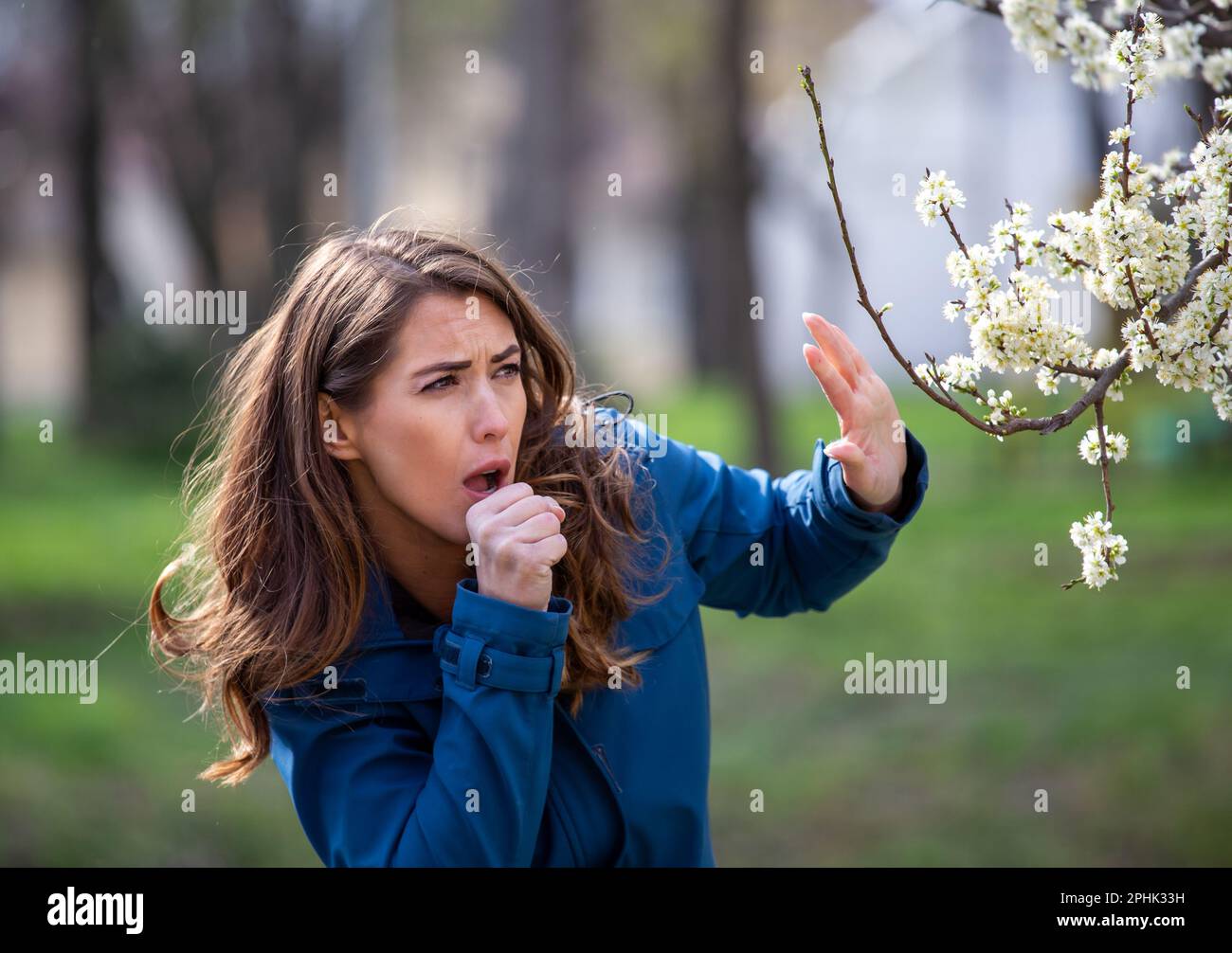 Pretty young woman standing in front of blooming tree in spring and ...