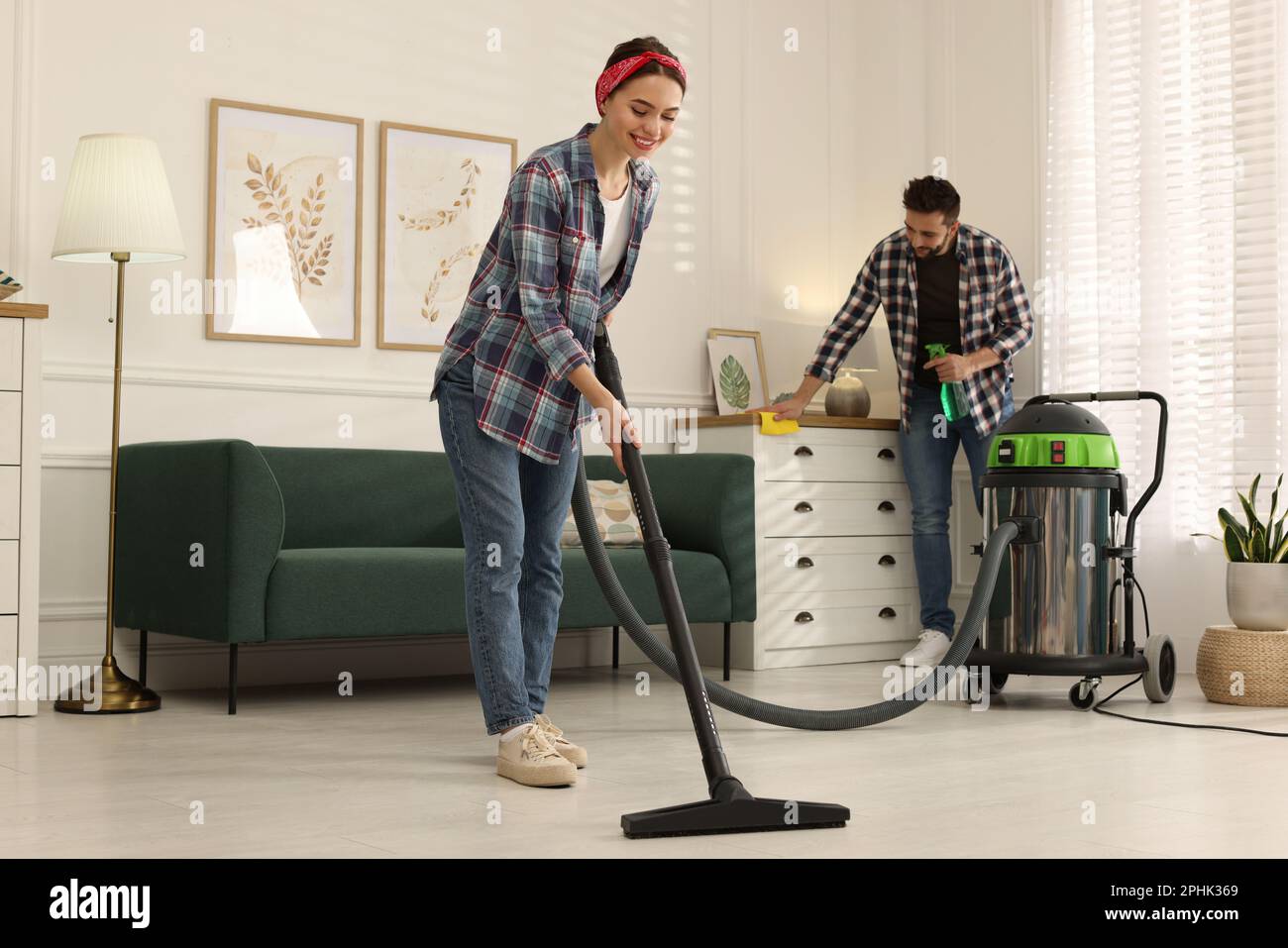 Couple cleaning up in living room together Stock Photo - Alamy