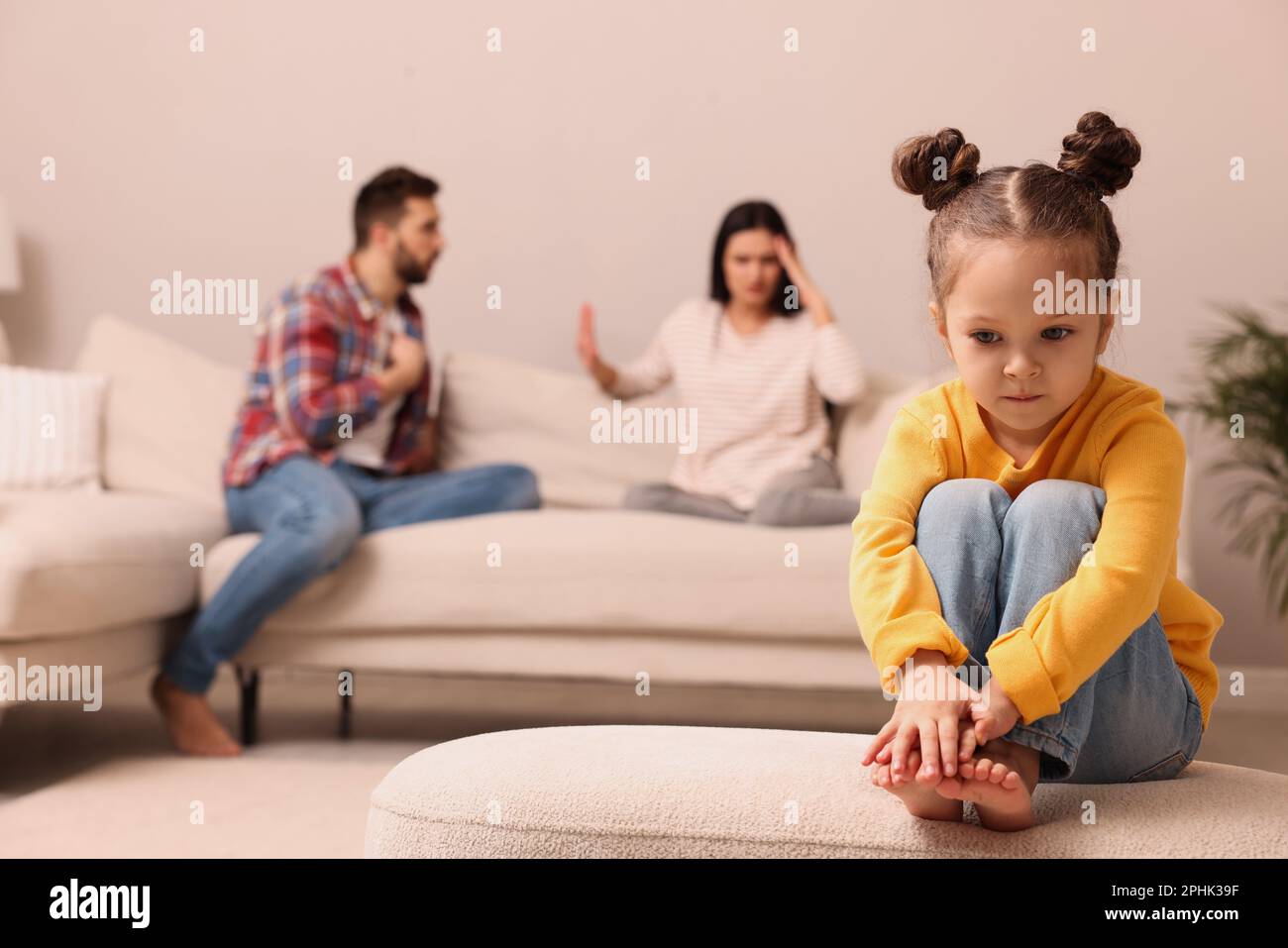 Sad little girl and her arguing parents on sofa in living room Stock ...