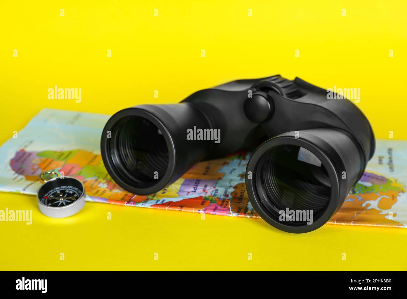 Modern binoculars, compass and map on yellow background, closeup Stock Photo - Alamy