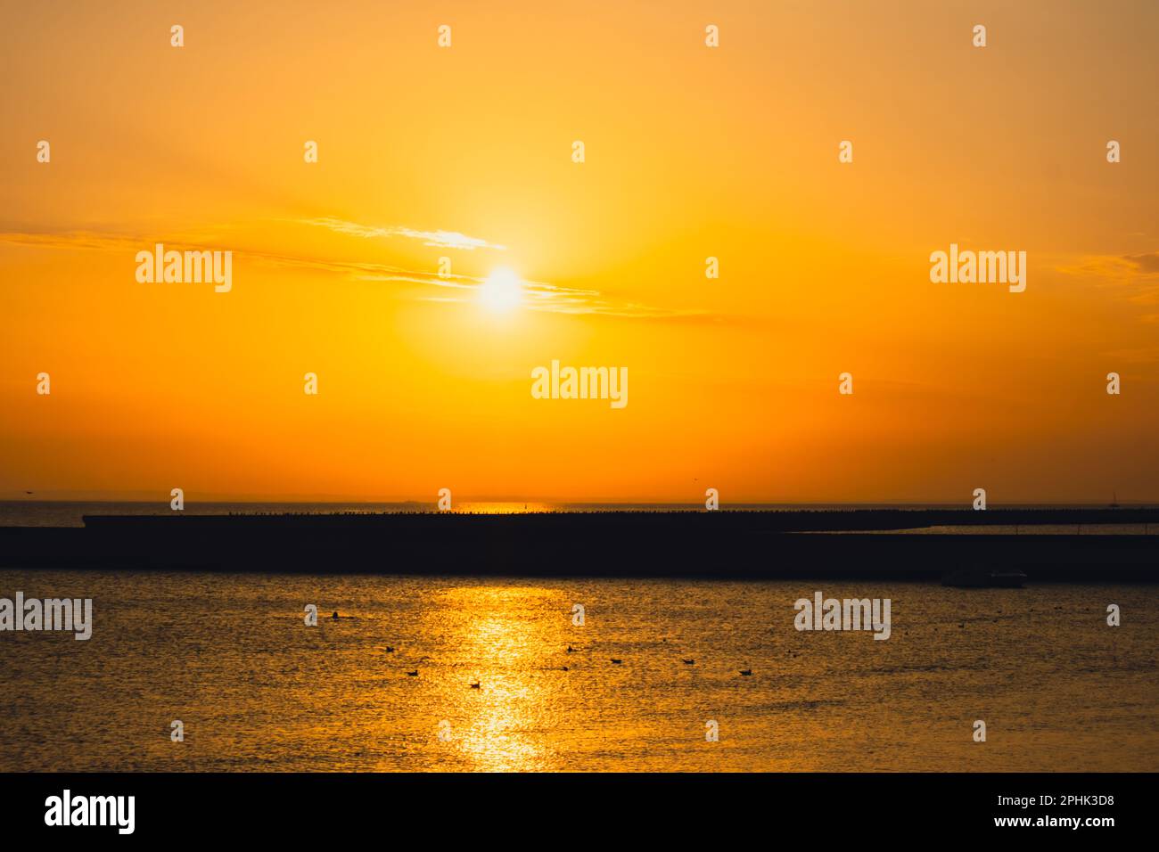 Reflection of sunlight over sea surface at sunset. Orange and gold blue ...