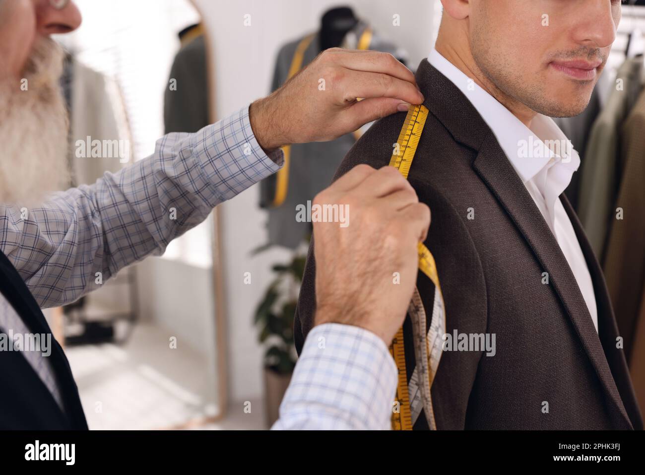 Professional tailor measuring shoulder seam length on client's jacket ...