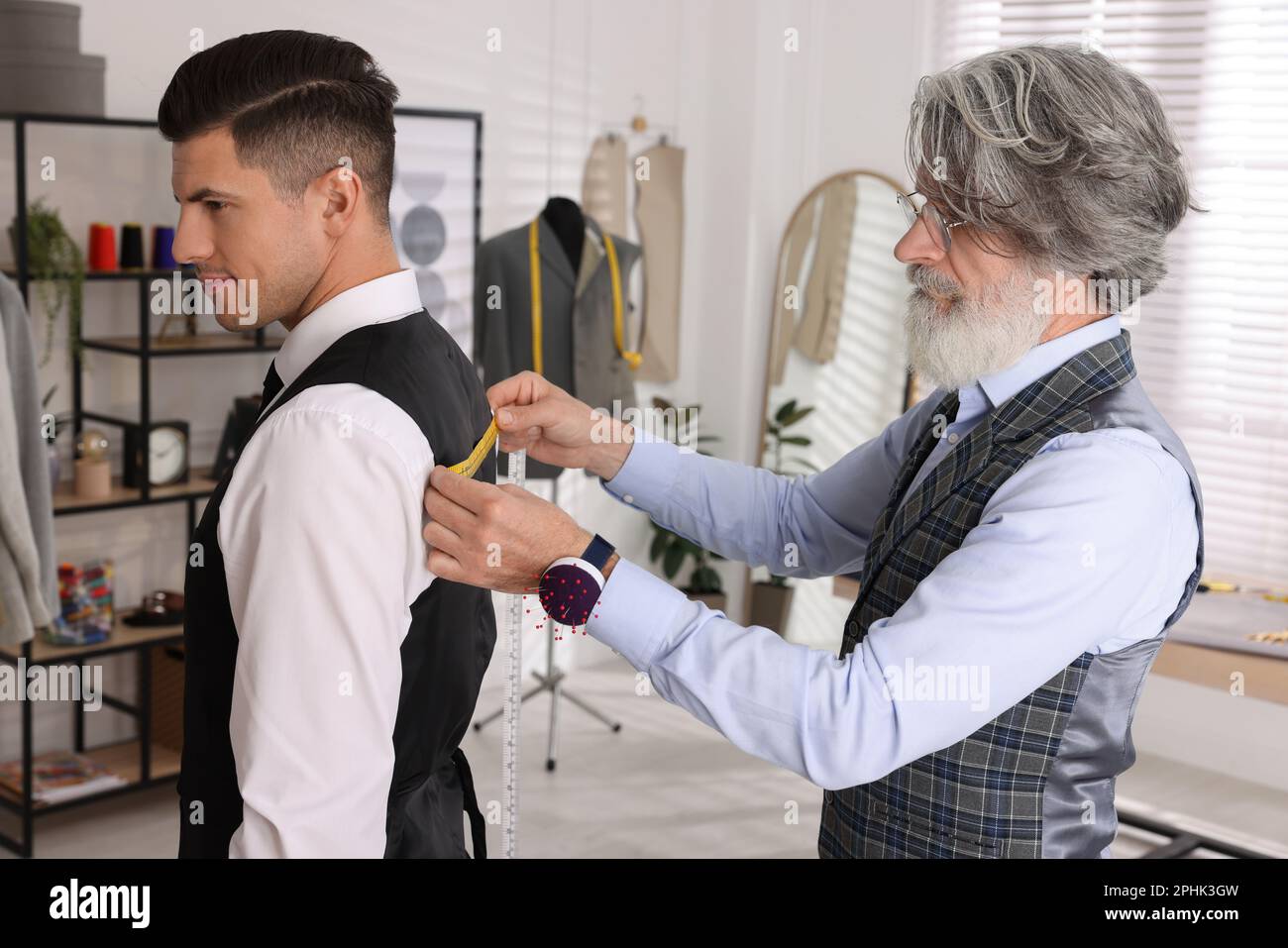 Professional tailor measuring client's back width in atelier Stock ...