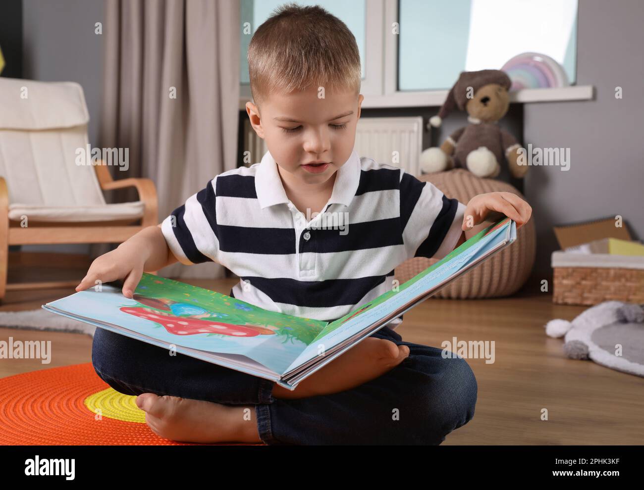 Cute little boy reading book on floor at home Stock Photo - Alamy