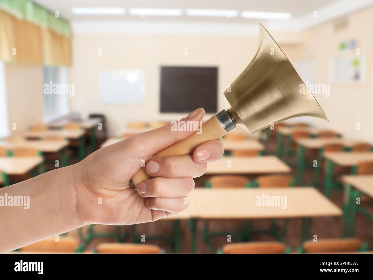Woman with school bell in empty classroom, closeup Stock Photo - Alamy