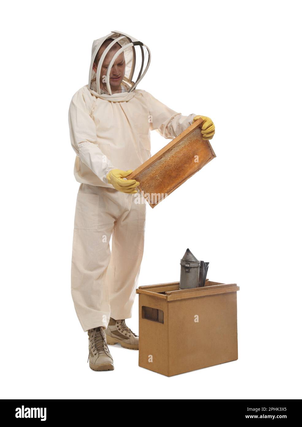 Beekeeper in uniform holding frame with honeycomb near wooden hive on ...
