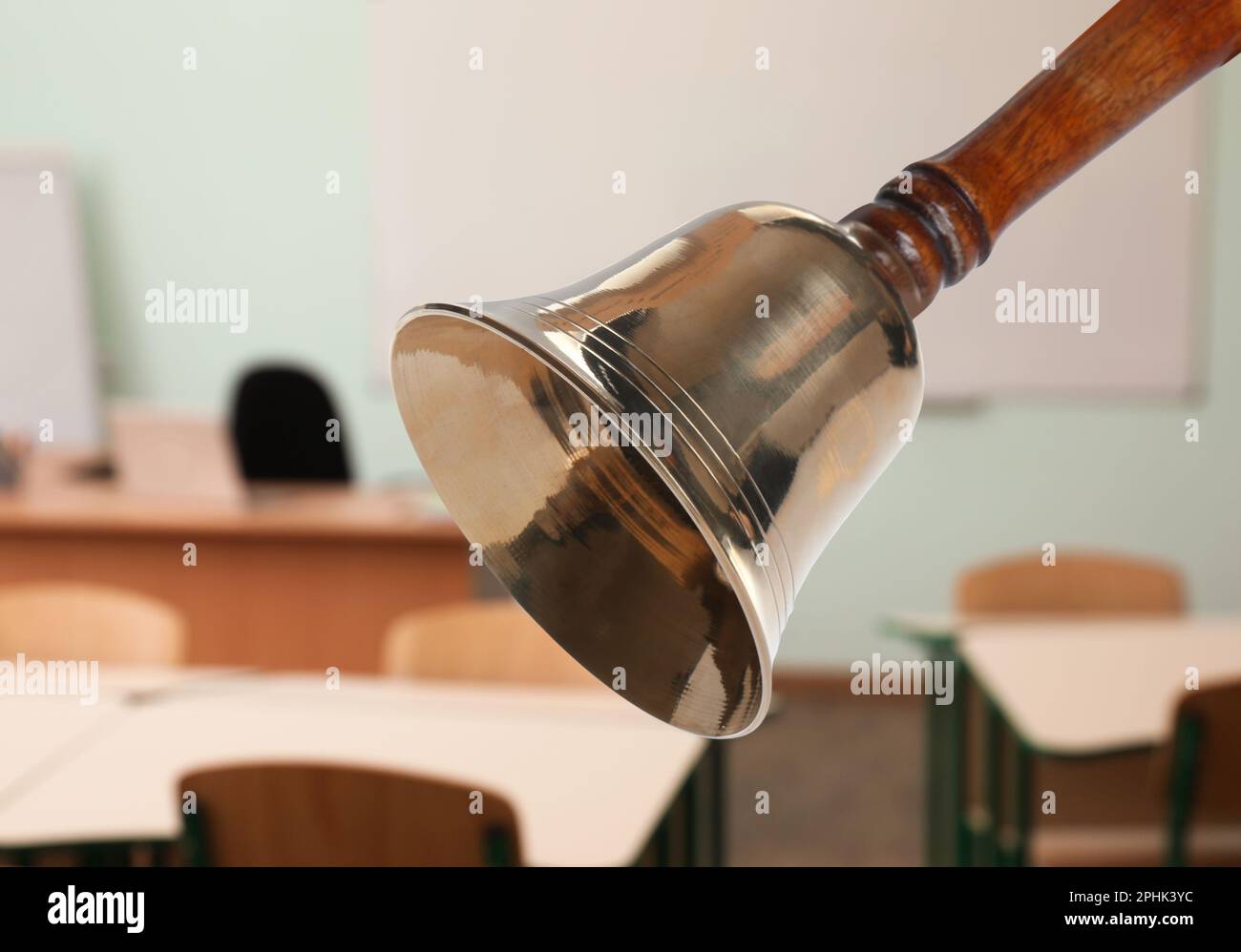 Golden school bell with wooden handle and blurred view of empty ...