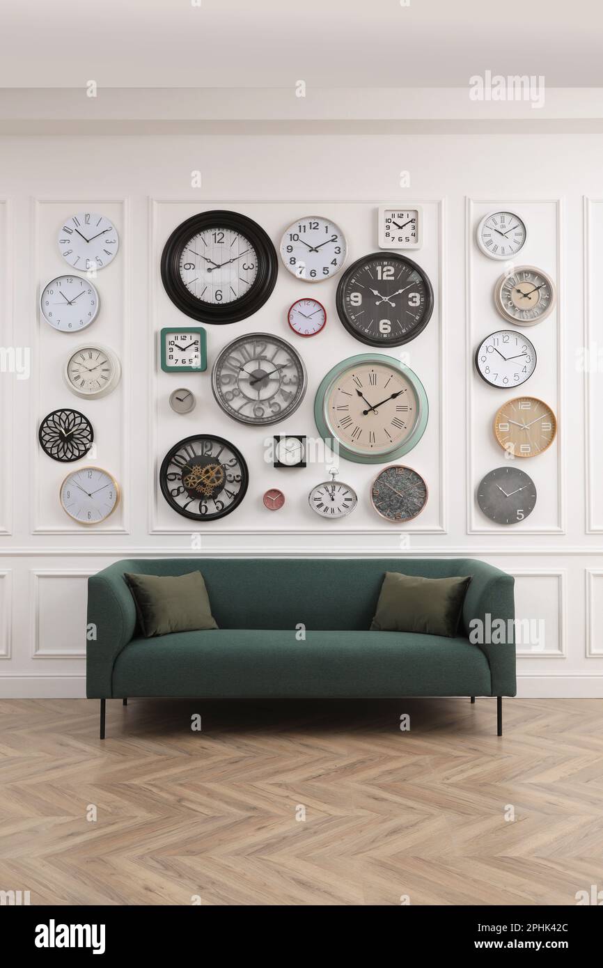 Collection of different clocks and comfortable sofa in stylish room ...