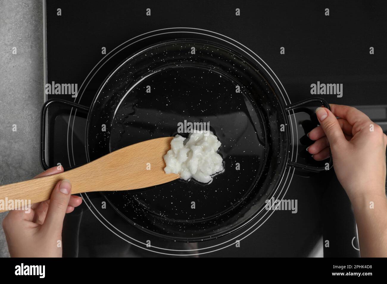 Woman cooking with coconut oil on induction stove, top view Stock Photo ...