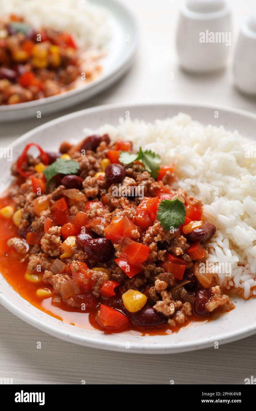 Plate of rice with chili con carne on white wooden table Stock Photo ...