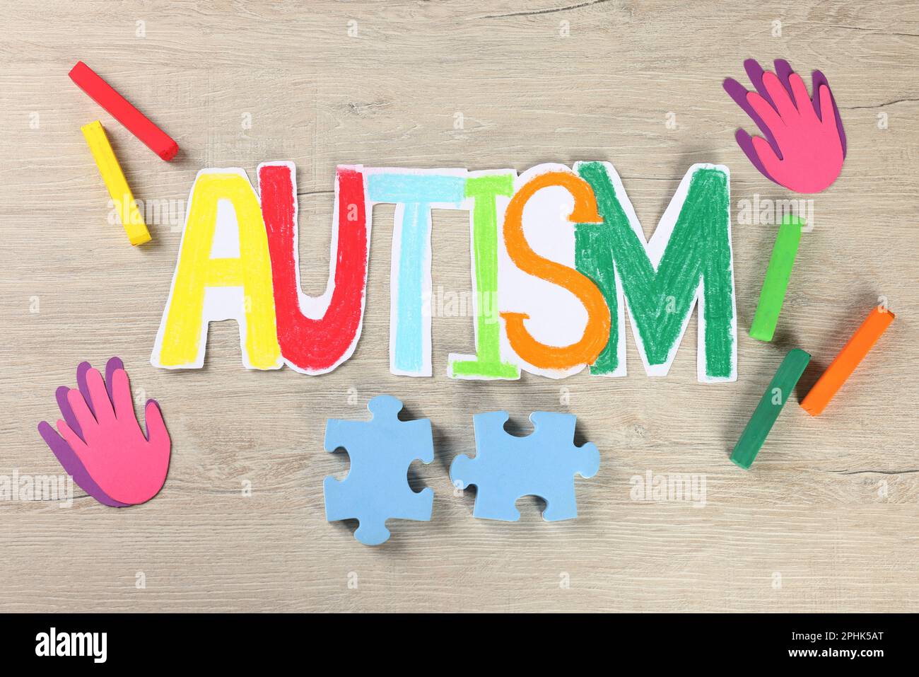 Word Autism made of paper, puzzle pieces and crayons on white wooden ...