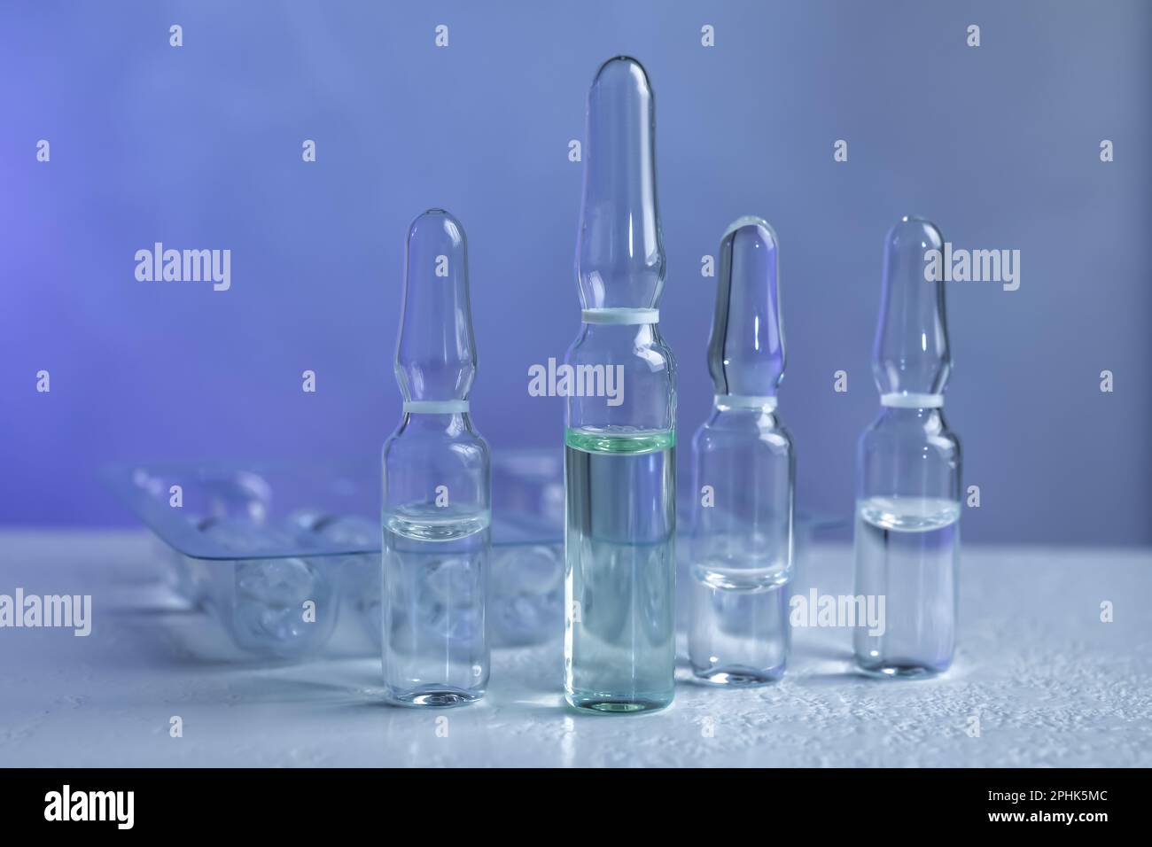 Pharmaceutical ampoules with medication on white table against color ...