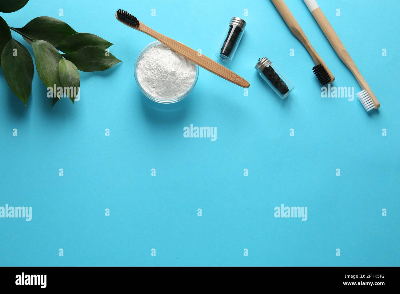 Bowl of tooth powder, brushes, dental flosses and plant on turquoise ...