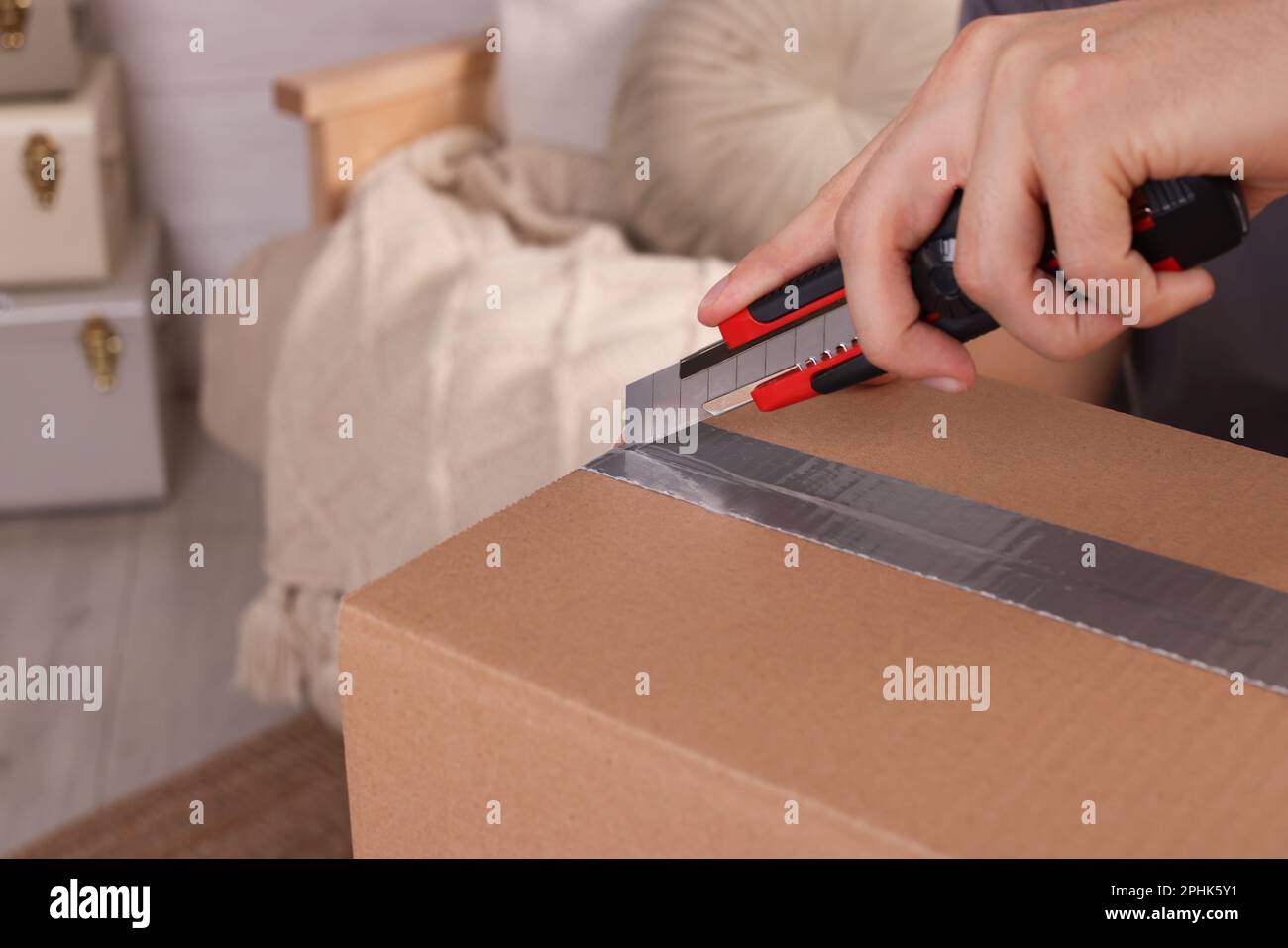 Man using utility knife to open parcel at home, closeup Stock Photo - Alamy