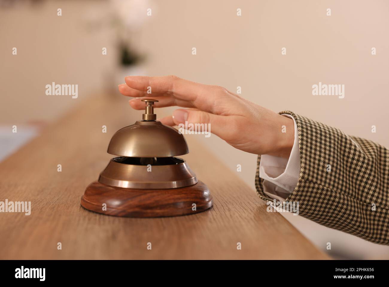 Woman ringing hotel service bell at wooden reception desk, closeup ...