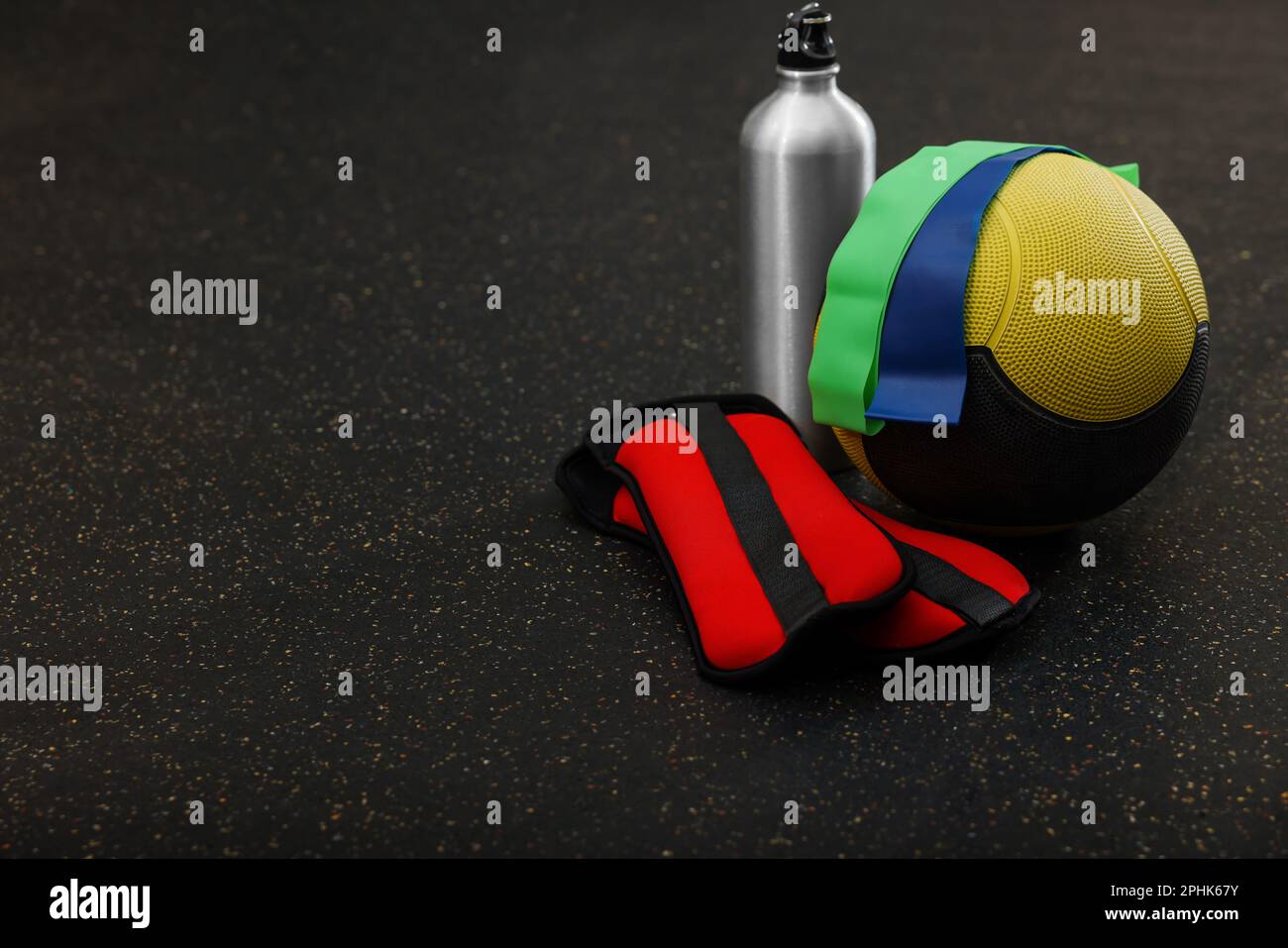 Medicine ball, bottle, ankle weights and elastic bands on floor, space ...