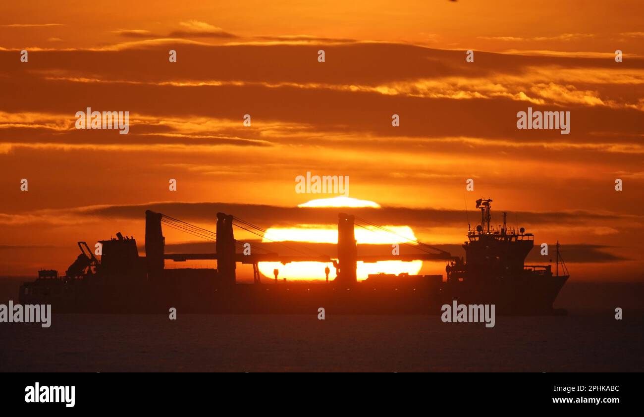 The cargo ship 'Maria' sits on the horizon as the sun rises over Brown ...