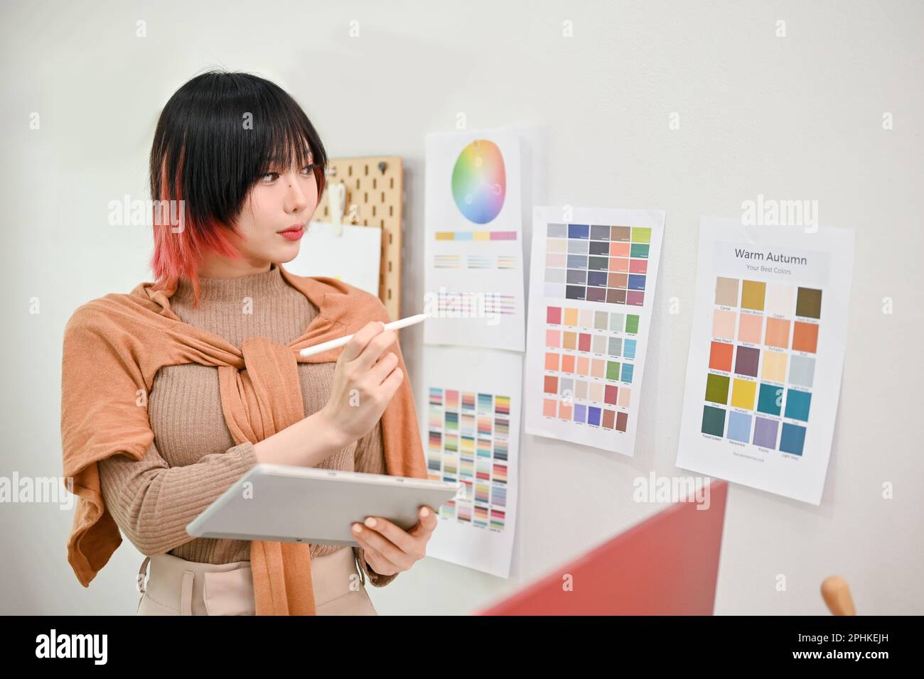 Attractive and focused young Asian female graphic designer working on ...