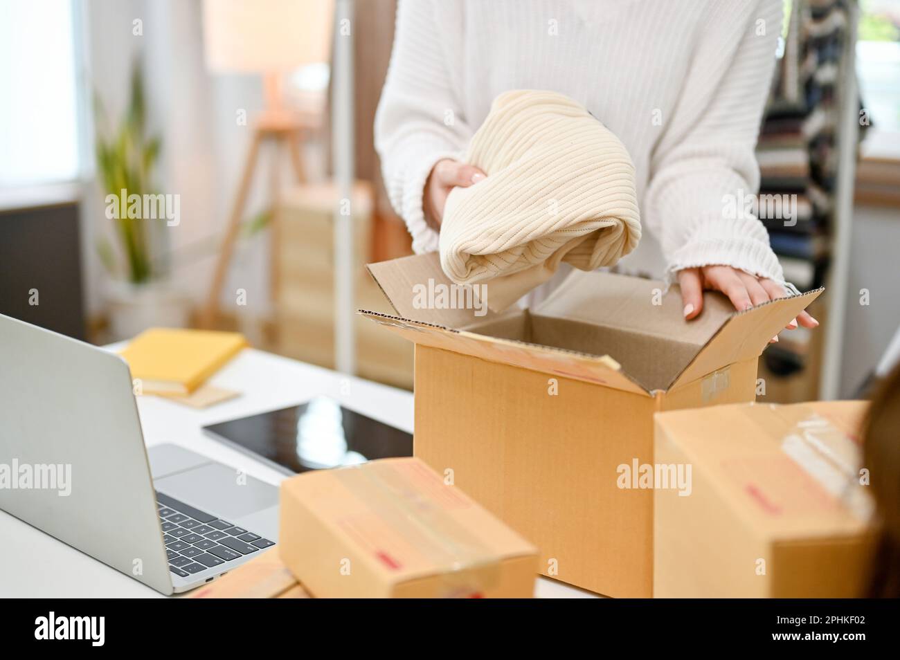 Close-up image of a female fashion clothing seller packing a shipping ...