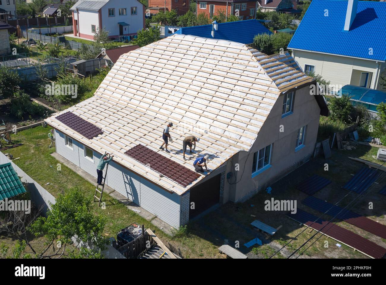Builders make a roof of metal shingles, aerial view Stock Photo - Alamy