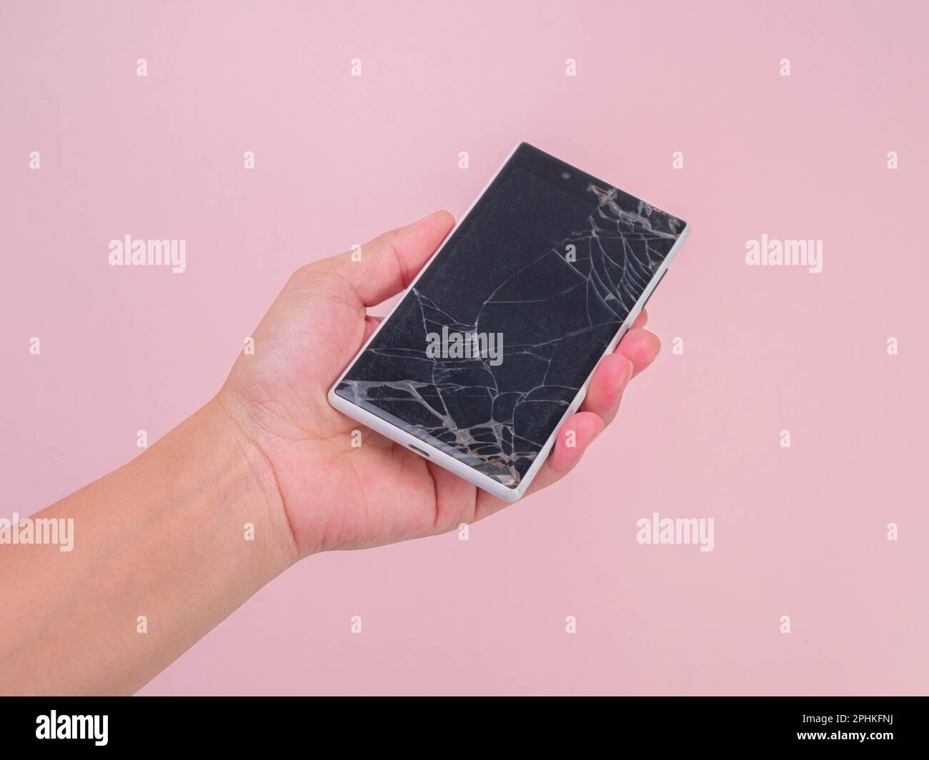 Close Up Of Hand Holding Mobile Phone With Broken Touch Screen On Pink