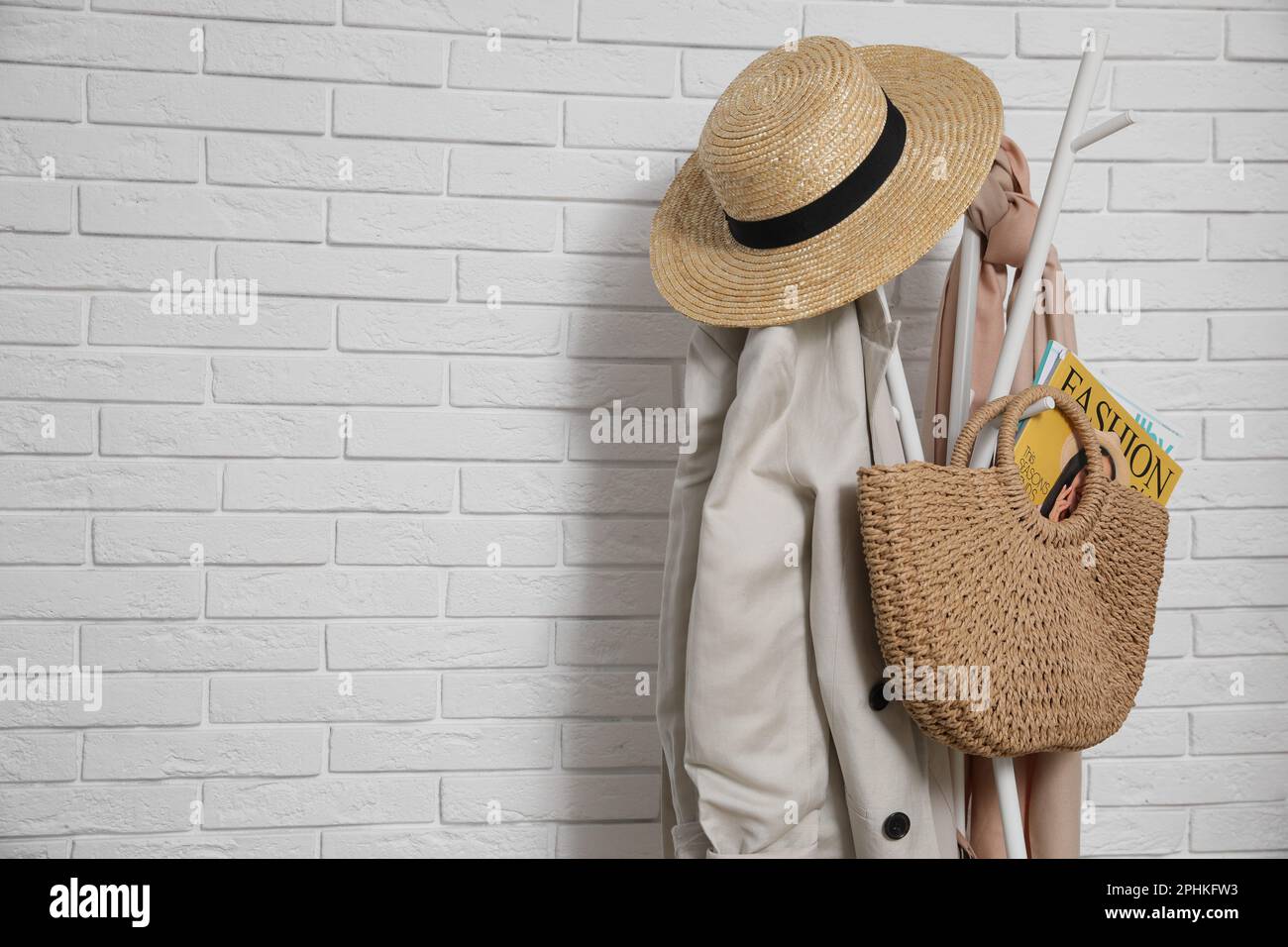 Coat rack with clothes and accessories near white brick wall in hallway ...