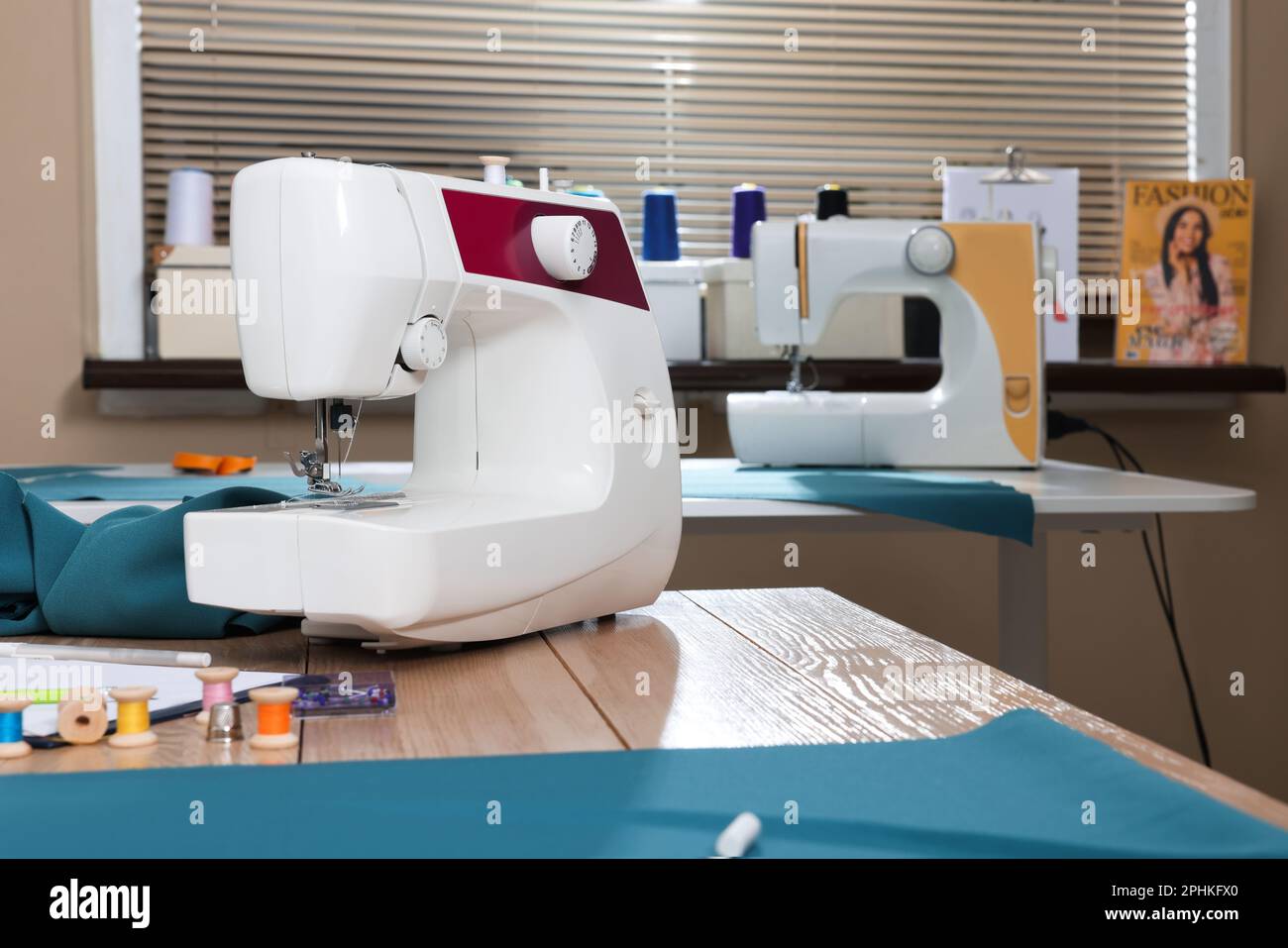 Sewing machine, fabric and equipment on table in dressmaking workshop ...