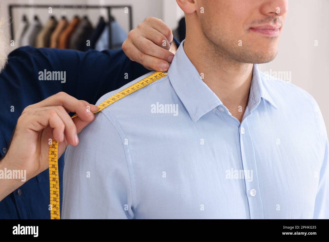 Professional tailor measuring shoulder seam length on client's shirt in ...