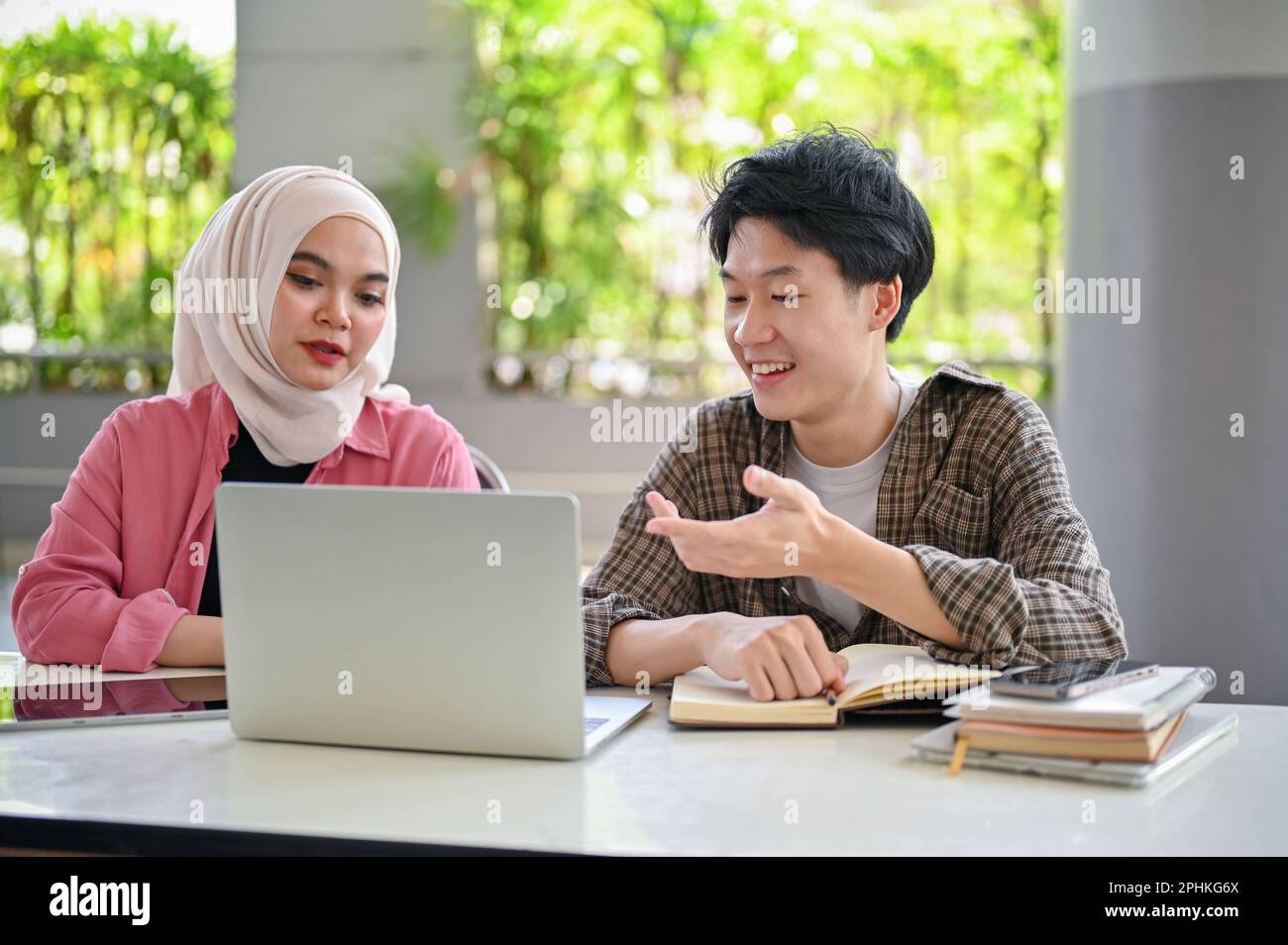 Smart young Asian male college student explaining and tutoring math to ...