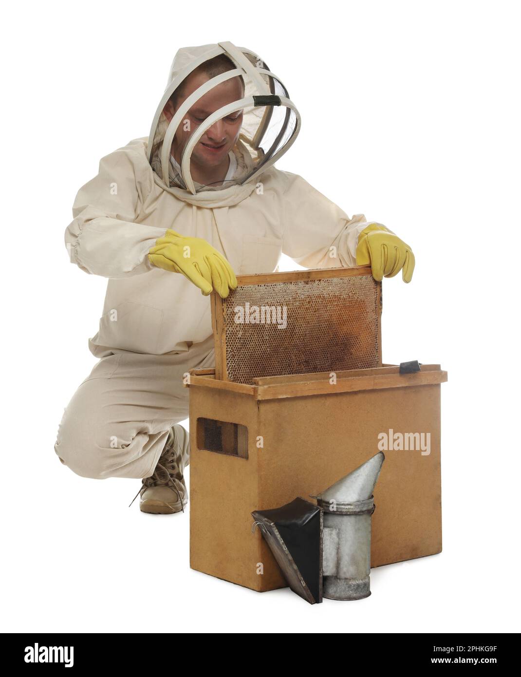 Beekeeper in uniform taking frame with honeycomb out of wooden hive on ...