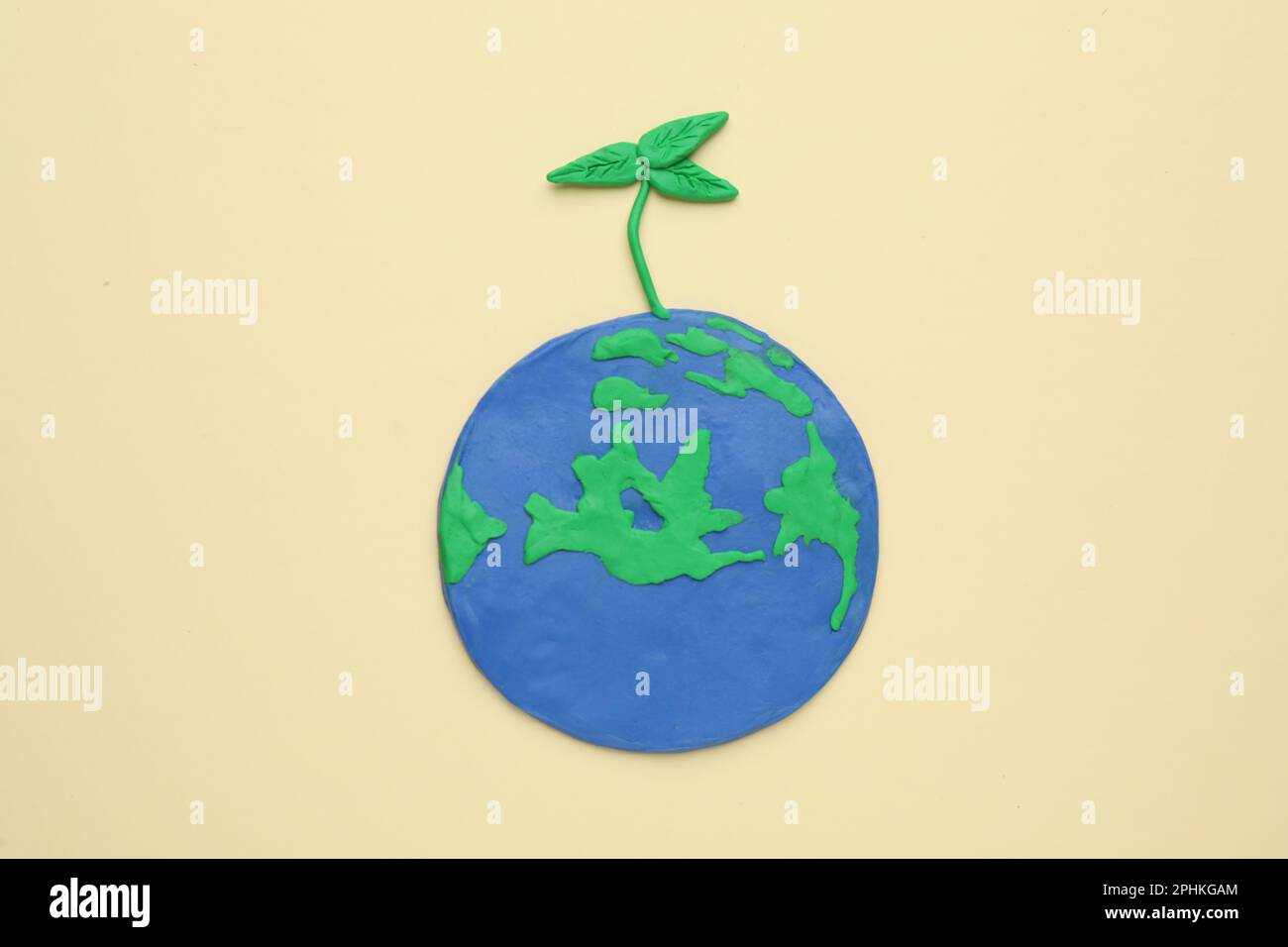 Plasticine model of planet with green seedling on beige background, top ...
