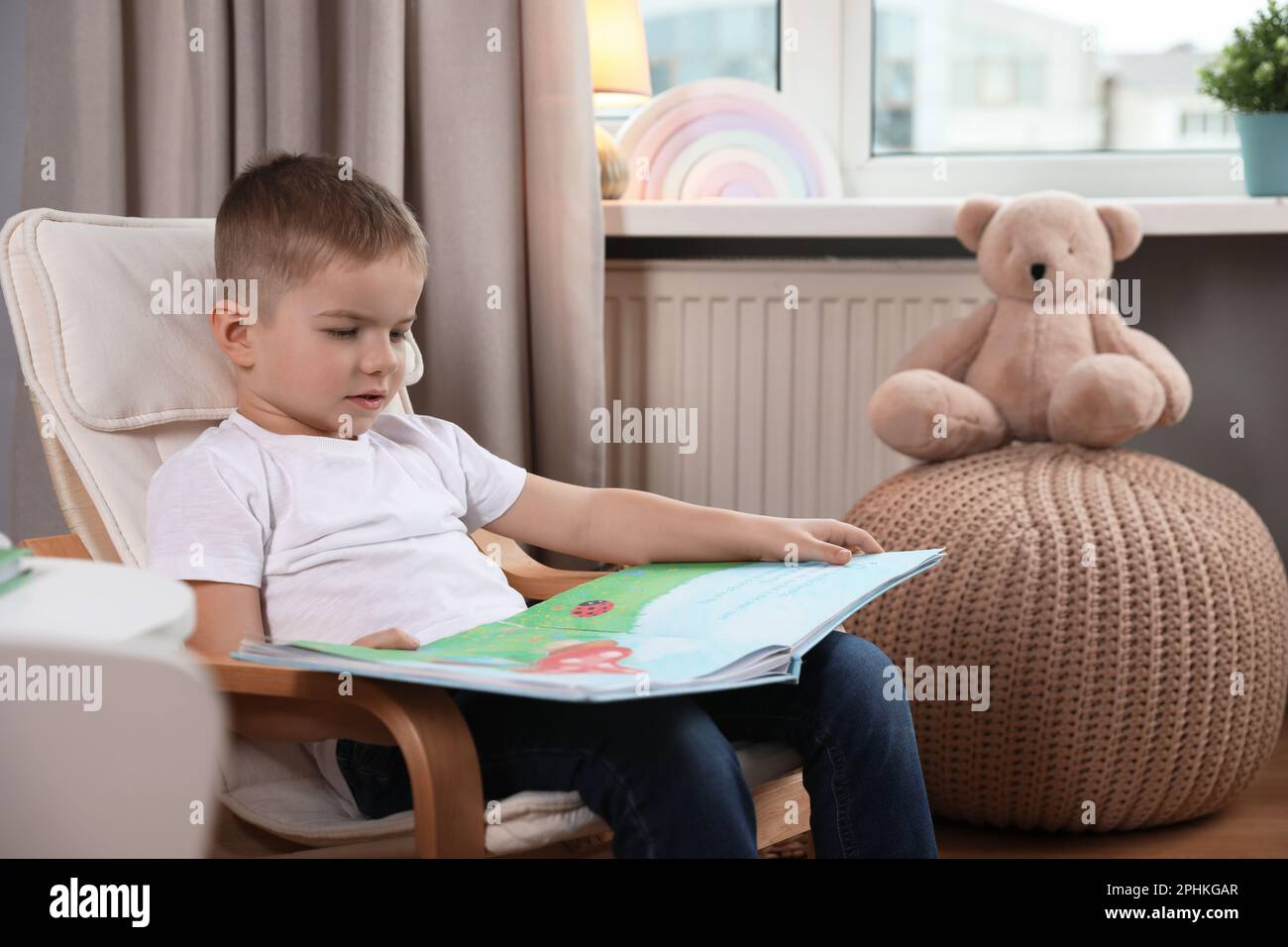Cute little boy reading book at home, space for text Stock Photo - Alamy