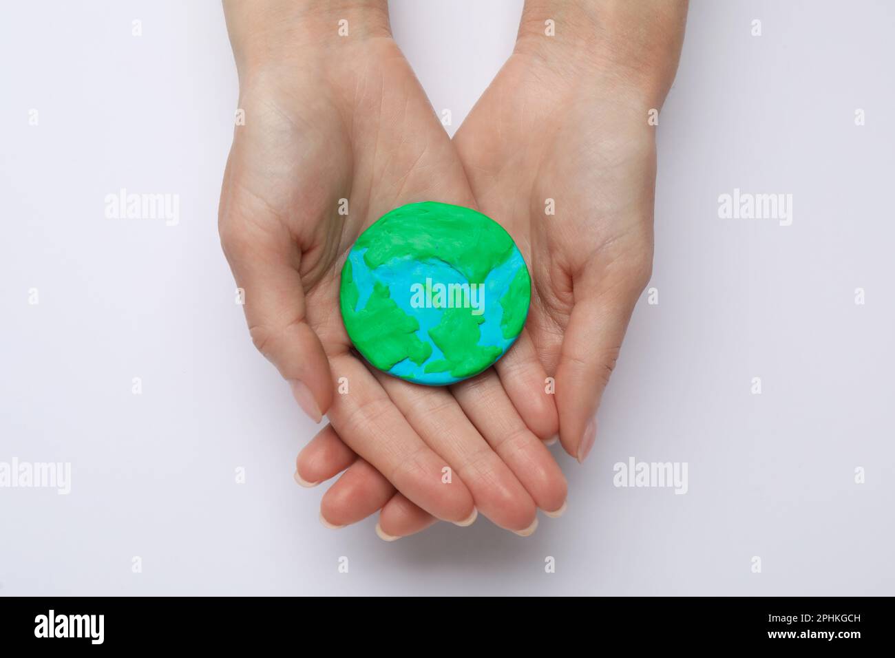 Woman holding plasticine model of planet on white background, top view ...