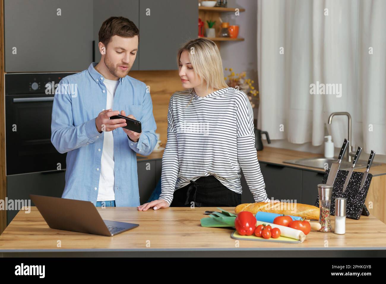 Smiling loving couple cooking salad together while standing on a ...
