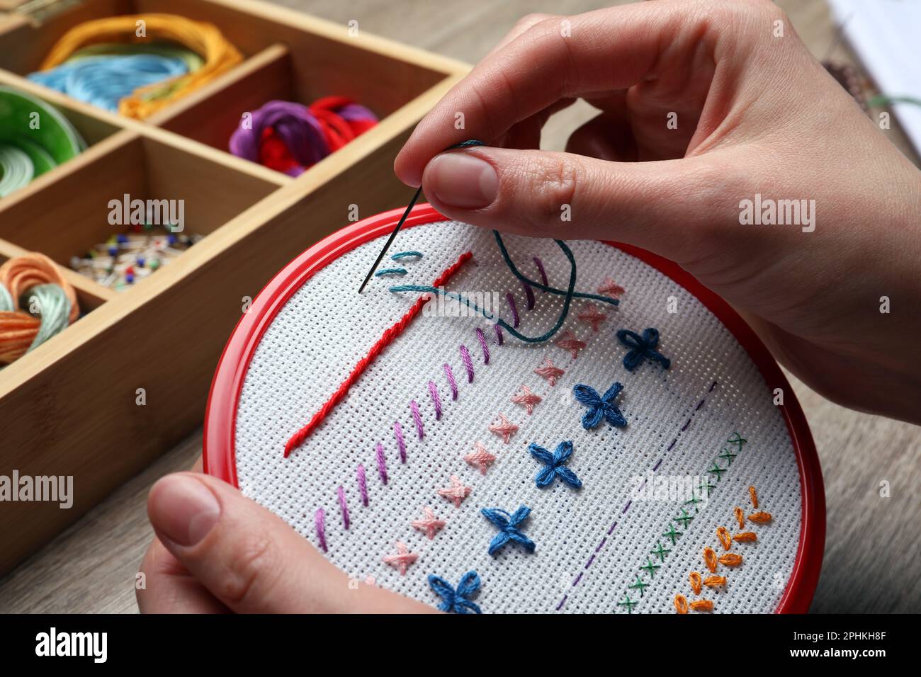 Woman doing different stitches with colorful threads on fabric in ...