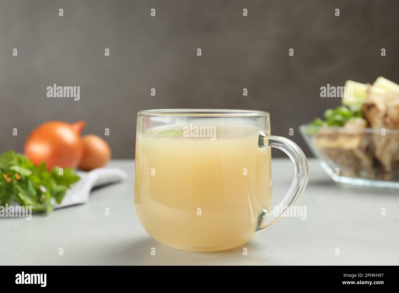 Glass cup of delicious homemade bone broth on light grey table Stock ...