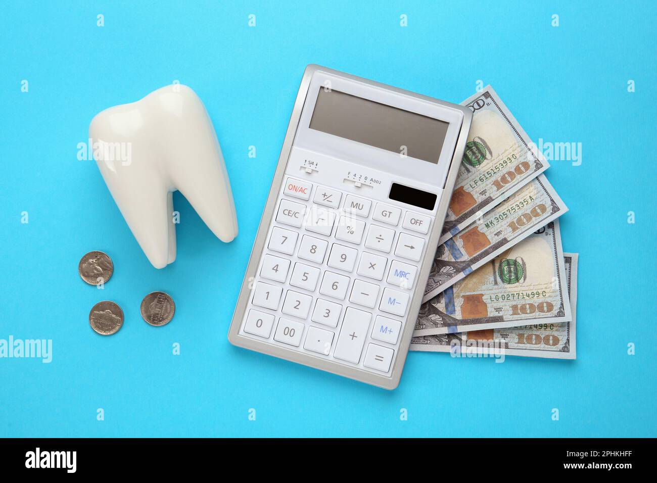 Ceramic model of tooth, money and calculator on light blue background ...