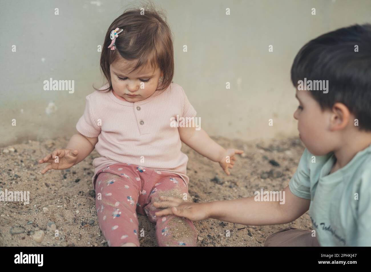 Small children playing with sand outdoors at home yard on a summer day ...